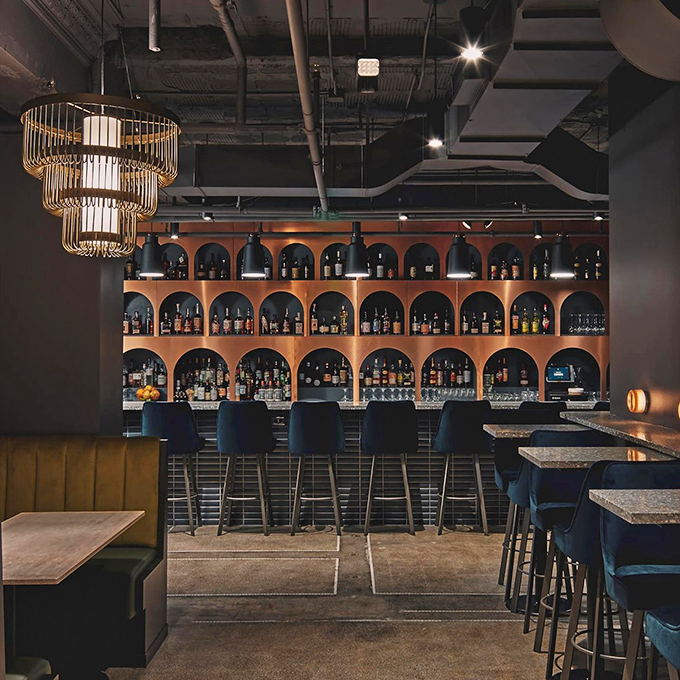 The elegant bar at Shelby showcases a stunning array of spirits in arched alcoves, like a cathedral dedicated to the art of mixology.