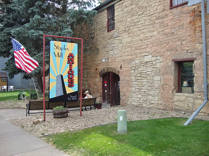 The sturdy limestone exterior of Staples Mill Antiques stands like a time portal, its colorful sign beckoning curious travelers into Stillwater's most fascinating treasure hunt.