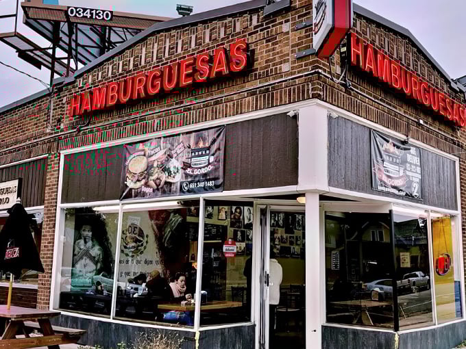 The brick facade with glowing red "HAMBURGUESAS" signage promises a flavor fiesta that bridges cultures and satisfies cravings.