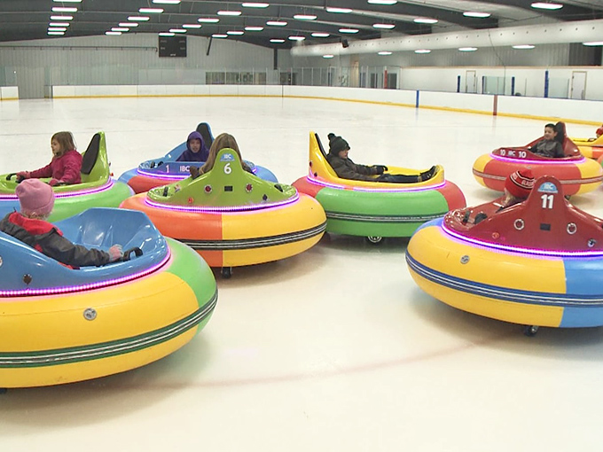 Colorful bumper cars await their pilots, each one a vibrant donut of potential joy on the gleaming ice surface.