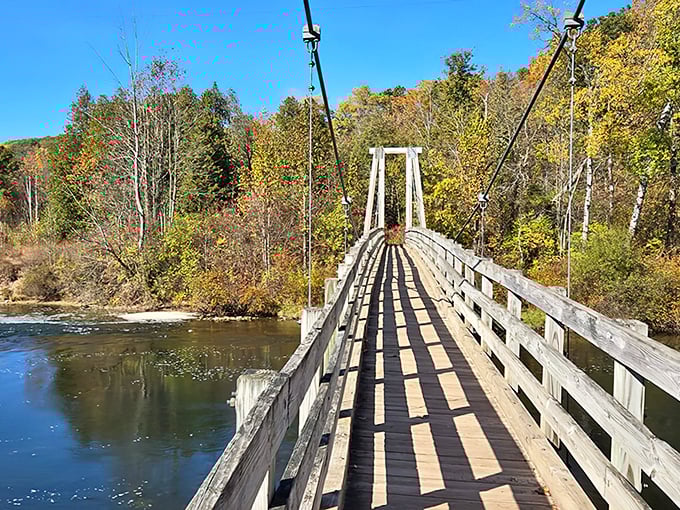 The iconic suspension bridge spans the Manistee River like a gateway to adventure, inviting hikers to cross between worlds of forest and water.
