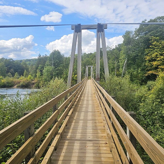 A wooden suspension bridge stretches across the Manistee River, inviting adventurers to cross into wilderness that seems straight from a storybook.
