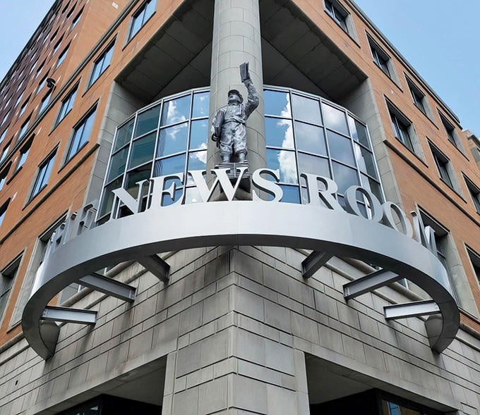 The News Room's iconic exterior features a triumphant paperboy statue, standing guard over downtown Minneapolis like journalism's own superhero.