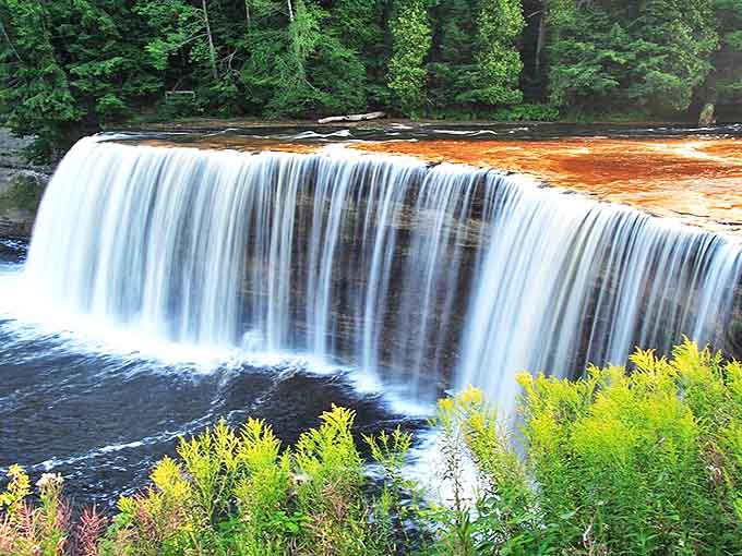 Nature's root beer cascade tumbles 50 feet in a hypnotic amber curtain, proving Michigan can drop jaws without saying a word.