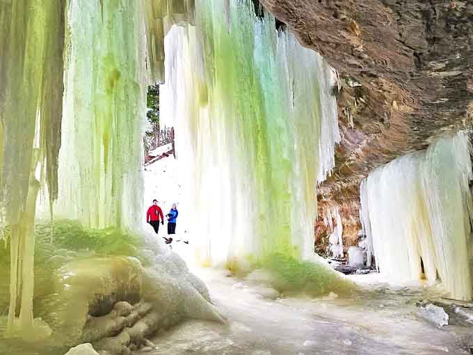 Massive ice curtains transform this Michigan cliff face into a frozen cathedral, where visitors explore nature's winter artistry.