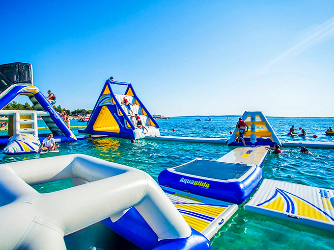 Vibrant blue and yellow inflatables create a floating playground paradise at Water Warrior Island, where summer dreams take shape on water.