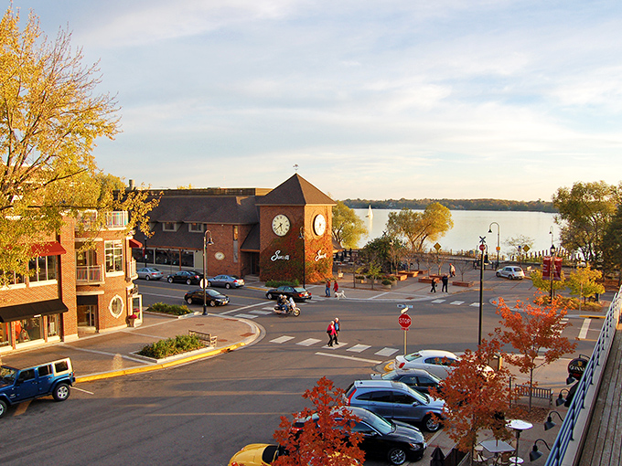 Wayzata's iconic clock tower stands sentinel over Lake Minnetonka, where autumn leaves paint the shoreline in gold and crimson hues.