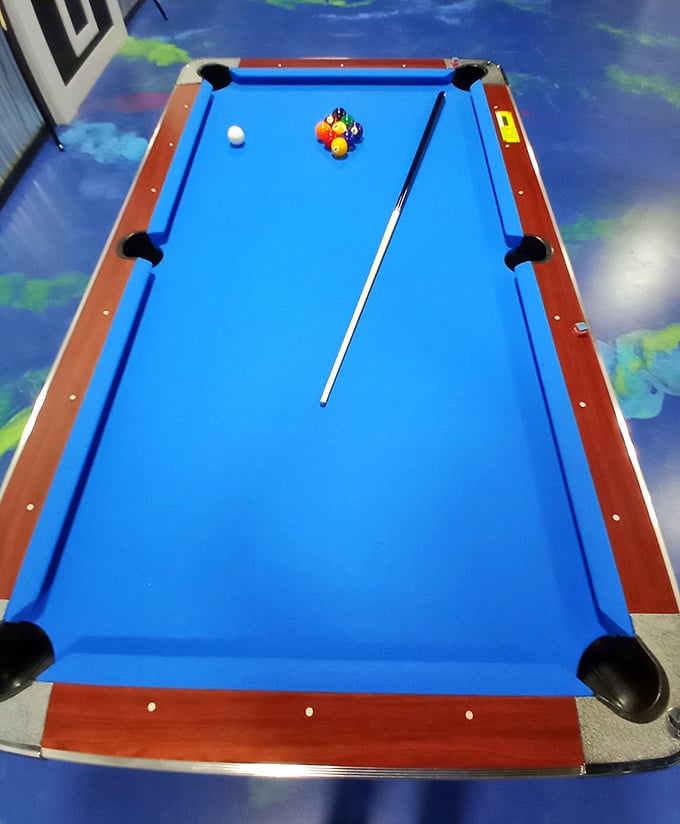 A pool table transformed by black light magic &ndash; where missing the eight ball feels like disappointing the universe itself.