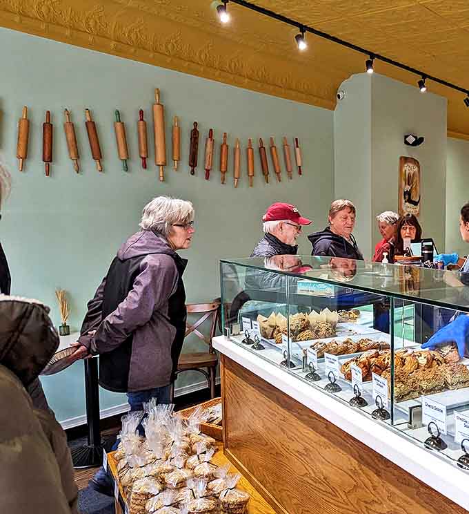Customers patiently waiting their turn, united by the universal language of great bread. The rolling pin display hints at the traditional techniques used behind the scenes.