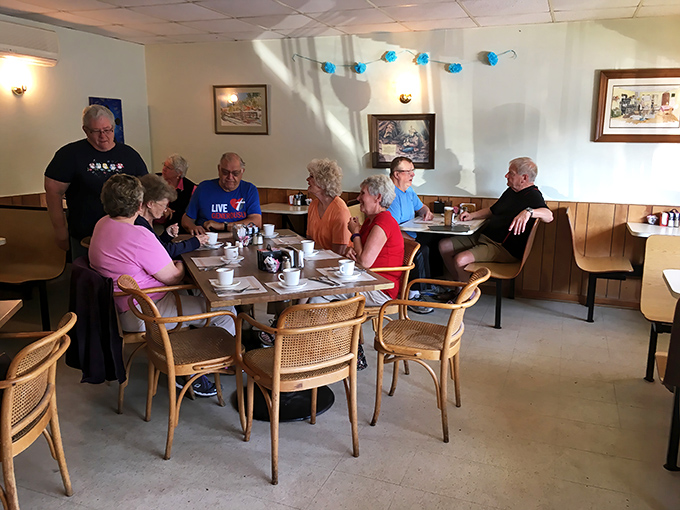 Local regulars gather around tables for conversation and coffee, creating the warm community atmosphere that makes small-town restaurants so special and irreplaceable.