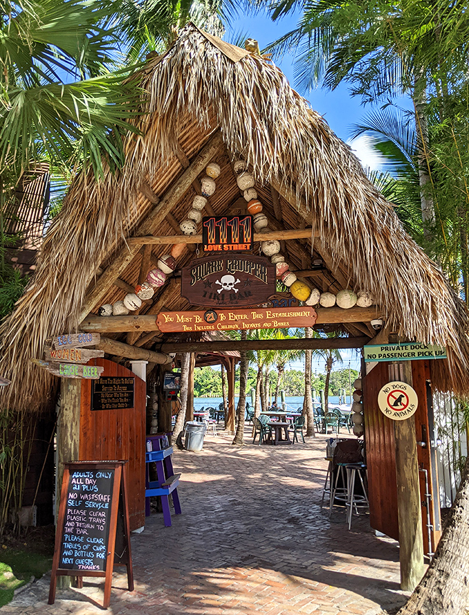 "You Must Be 21 To Enter" warns the sign beneath the thatched roof entrance, where palm fronds frame your path to relaxation.