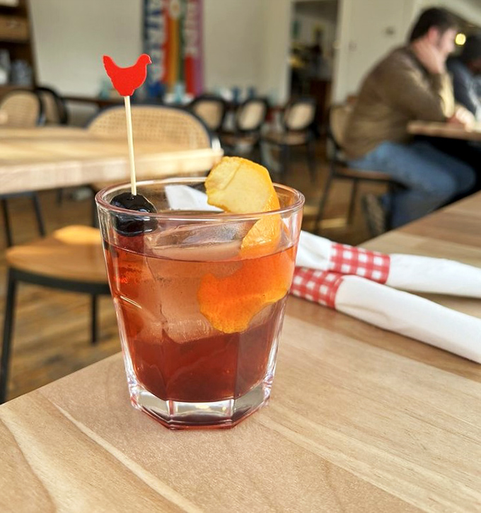 The maple old-fashioned comes garnished with an orange peel and whimsical chicken pick &ndash; serious cocktail craftsmanship with a playful wink.