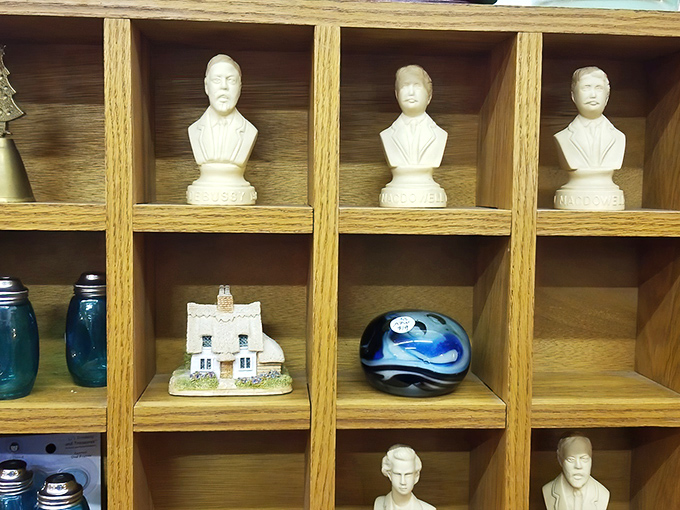 Miniature busts and collectibles stand at attention in wooden cubbies, like tiny sentinels guarding memories of bygone eras.