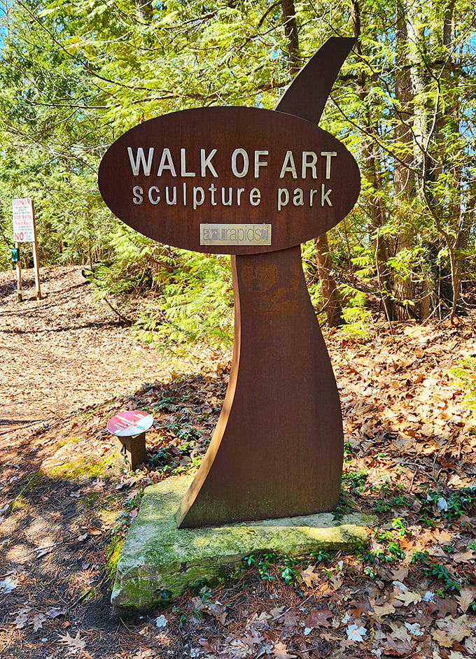 The park's distinctive signage serves as both wayfinding and art piece &ndash; a curved metal form that introduces visitors to this woodland gallery.