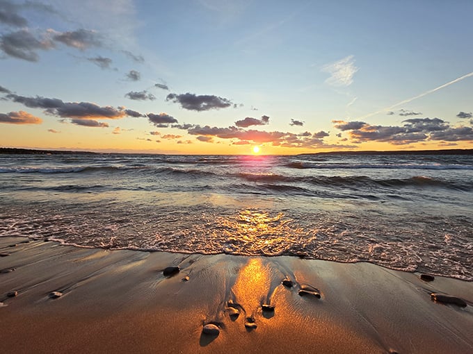 Sunset paints Little Traverse Bay in liquid gold, where gentle waves create a symphony of light that no photograph can fully capture.