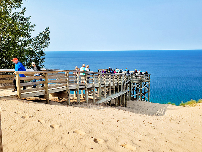 Visitors gather at the wooden observation deck, collectively experiencing that "I can't believe this is Michigan" moment as they gaze over endless blue.