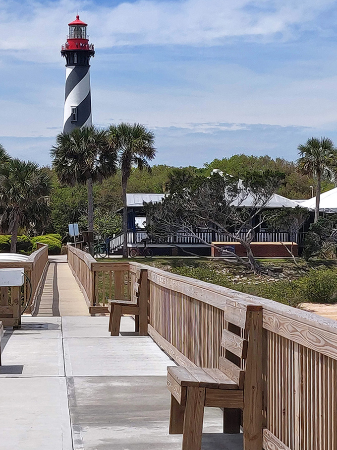 A wooden boardwalk leads visitors toward the towering lighthouse, creating a perfect frame for that "I was here" vacation photo.