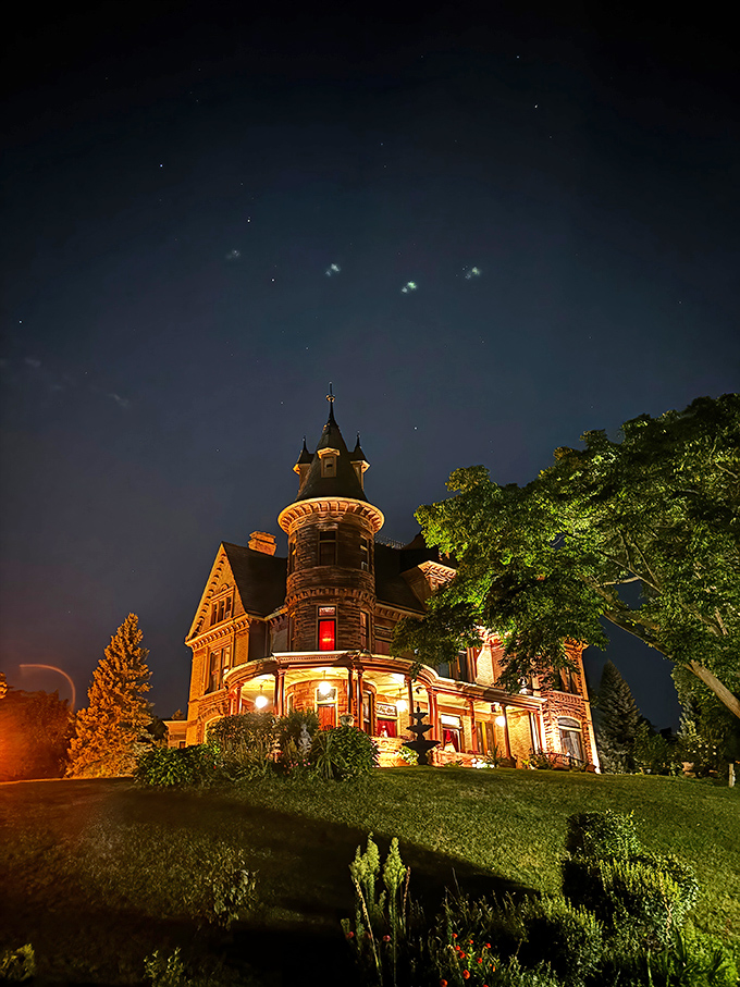 As darkness falls, Henderson Castle transforms into a glowing beacon, its illuminated turret a magical sight against the night sky.