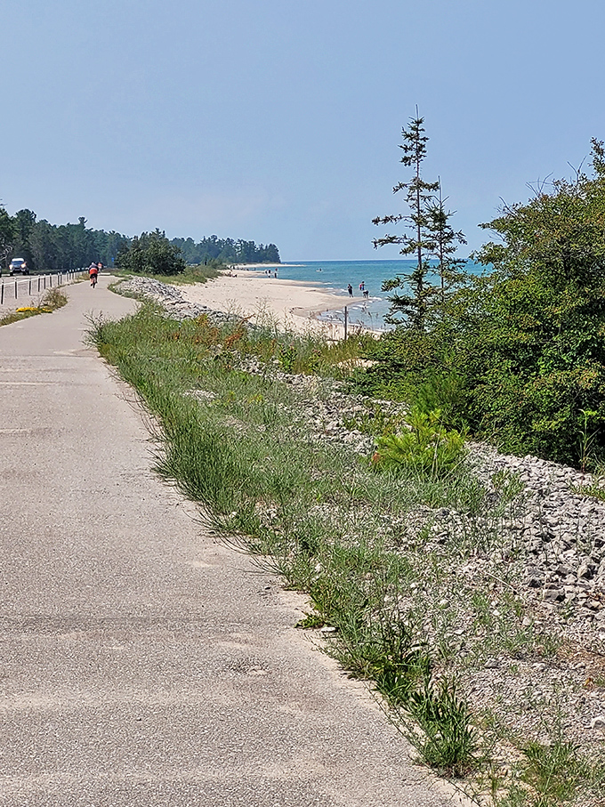 The coastal pathway invites leisurely exploration, with the beach beckoning just beyond the greenery like a sandy promised land.
