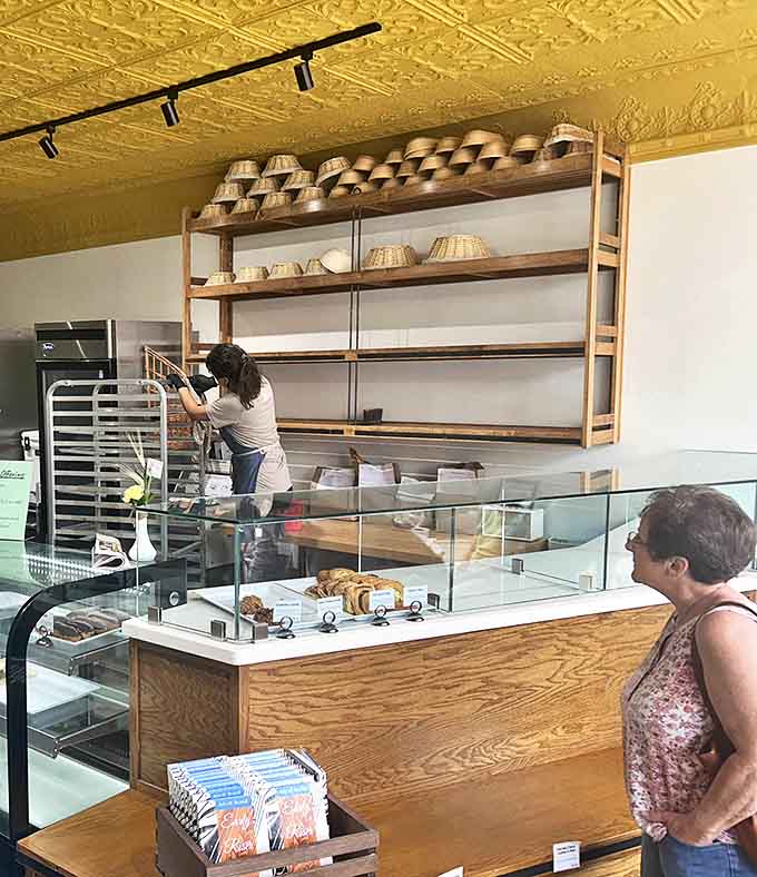 The service counter where dreams come true and diets go to die. Each wooden shelf awaits its daily parade of freshly baked treasures.