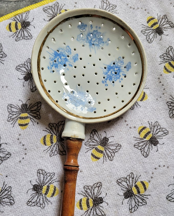 This delicate strainer with blue floral details once separated tea leaves from proper conversations in someone's cherished kitchen.