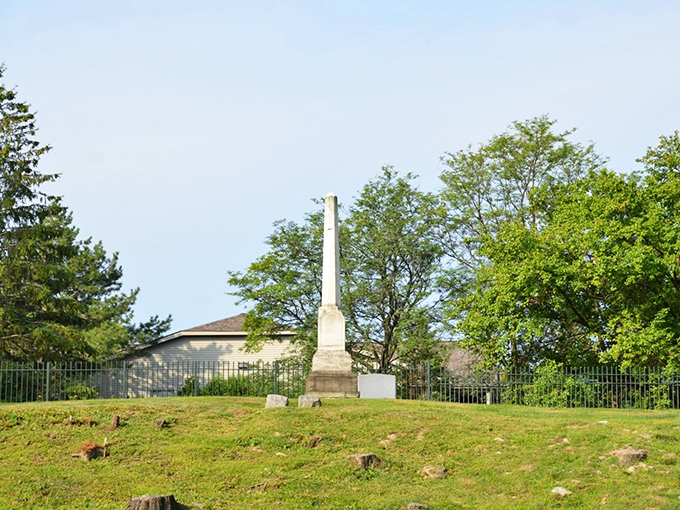 Summer's lush greenery embraces this simple obelisk, demonstrating how Elmwood's natural beauty enhances its historical significance.