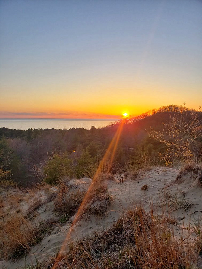 Mother Nature's grand finale: a Lake Michigan sunset paints the sky in impossible colors, turning dune silhouettes into works of art.