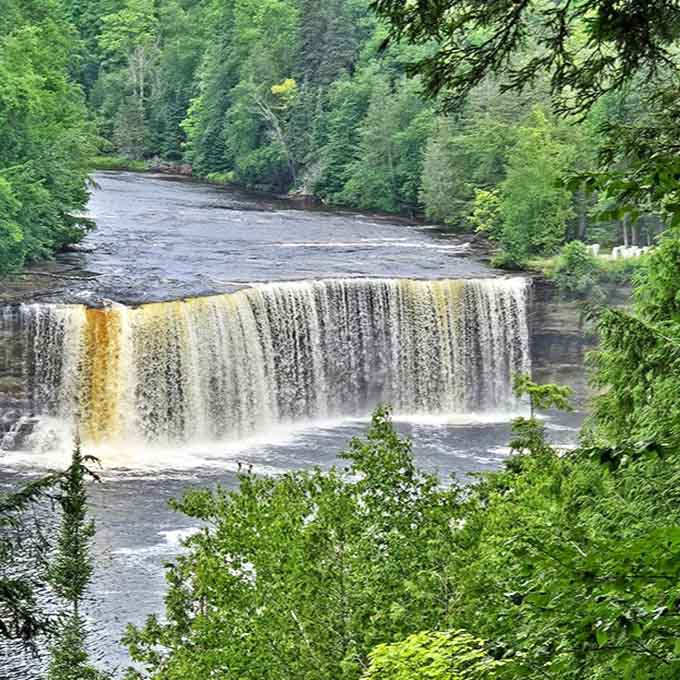 Nature frames Upper Tahquamenon Falls with lush greenery, showcasing its breathtaking beauty.