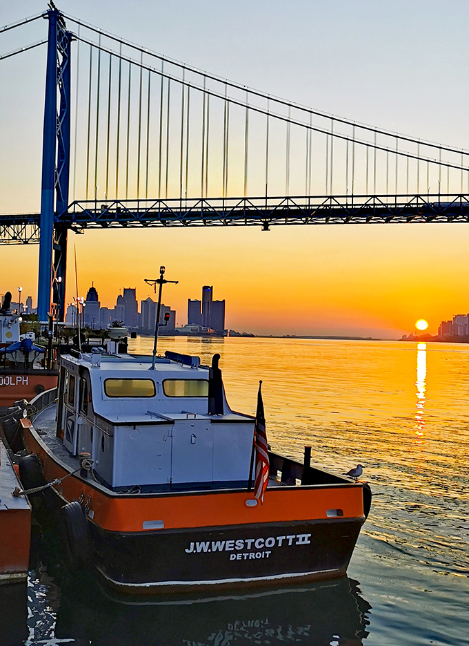 Silhouetted against a fiery sunset, the J.W. Westcott II cuts a dramatic figure beneath the Ambassador Bridge's sweeping span.