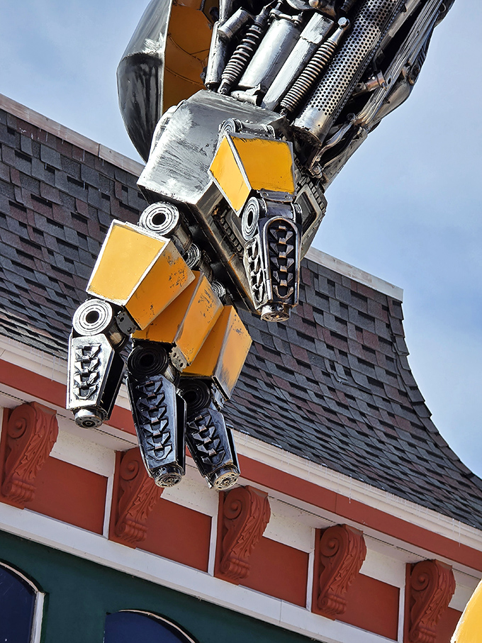 The detailed craftsmanship extends to every extremity, with the robot's hand showcasing the artist's ability to create expressive gestures from industrial materials.