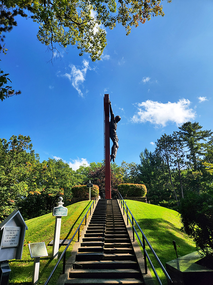 The dramatic crucifix rises against a brilliant blue Michigan sky, with steps leading visitors on a literal and spiritual ascent.