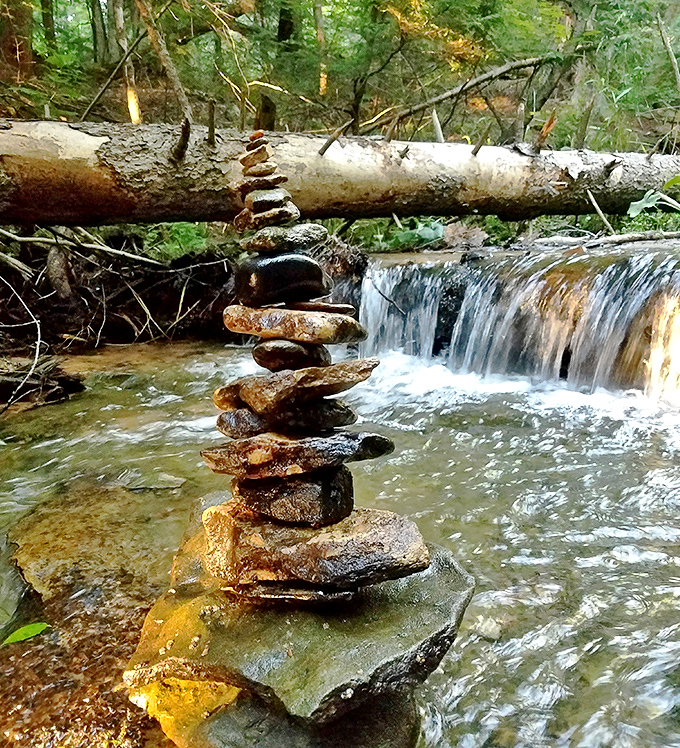 Stone balancing art adds human creativity to nature's canvas, a meditative practice reflecting the falls' perfect equilibrium.
