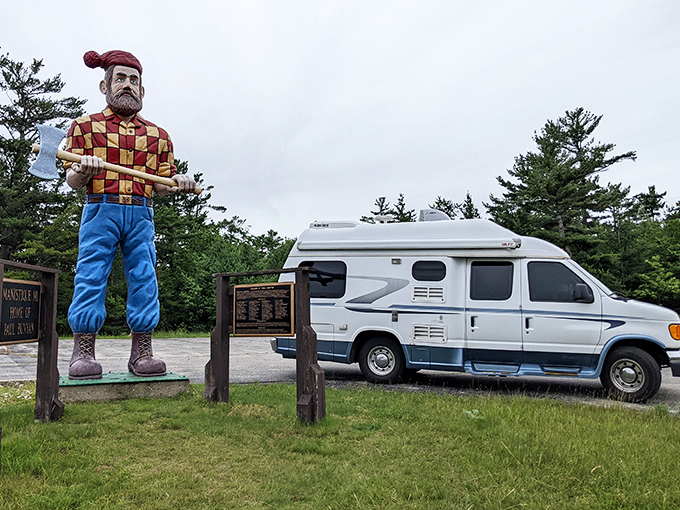Even parked vehicles look miniature beside this towering folk hero, demonstrating the impressive scale of this roadside attraction.