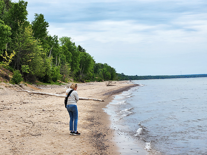 The thrill of discovery: A beachcomber pauses at the water's edge, where each wave might deliver a new geological treasure.