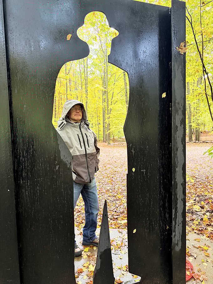 A visitor frames themselves perfectly within a silhouette cutout, becoming part of the art in a moment of playful interaction.