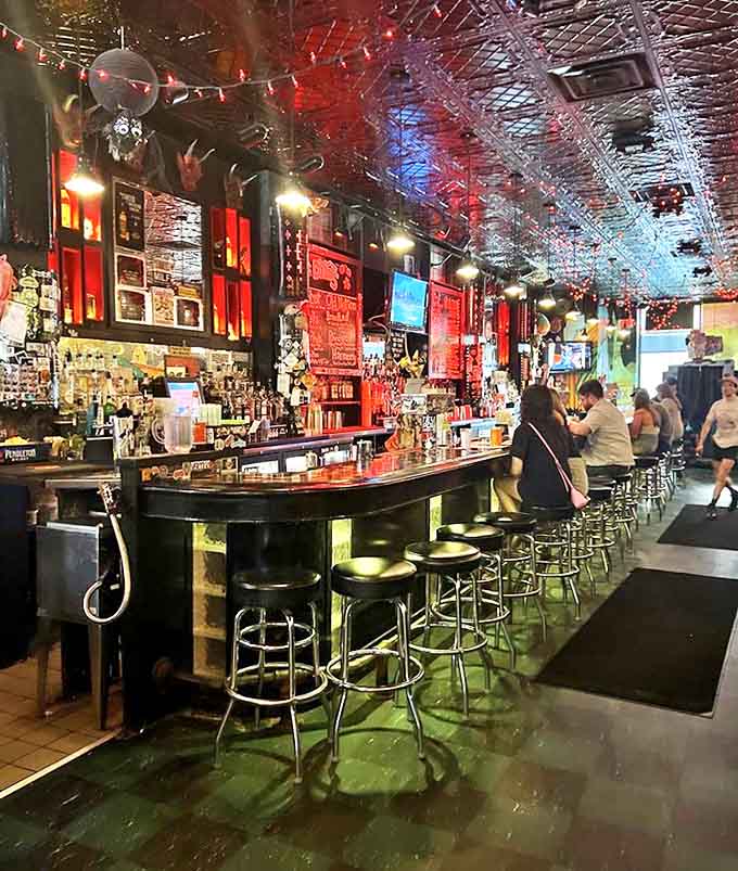 The bar stretches into infinity, a wonderland of bottles and taps where mixologists create liquid magic under the glow of string lights and tin ceiling reflections.