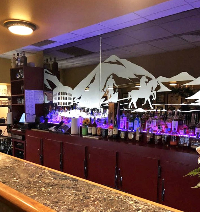 The bar area glows with blue light, while Roman-inspired silhouettes create dramatic shadows against the wall of premium spirits.