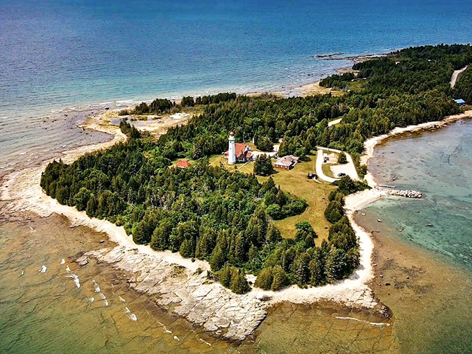 Aerial splendor reveals the lighthouse's strategic position, with shorelines embracing the peninsula like protective arms around a maritime treasure.
