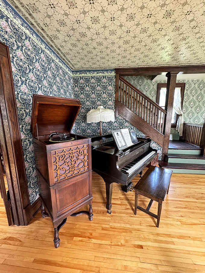 Another angle of the beautifully preserved living space featuring an antique phonograph cabinet and piano where musical talents might have first blossomed.