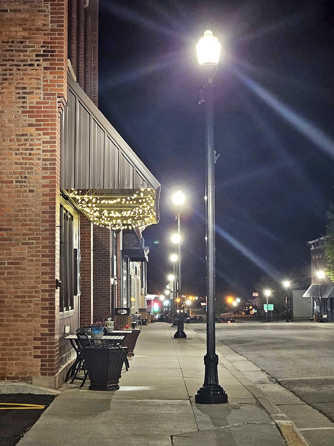 Night falls softly on brick storefronts where string lights twinkle like earthbound stars guiding evening wanderers.