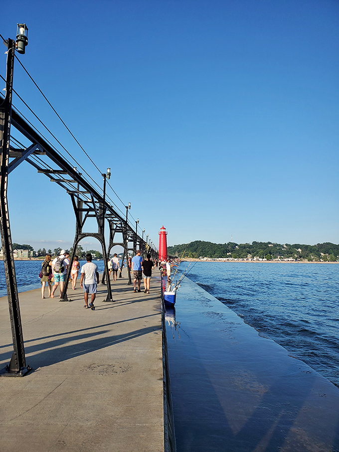 Visitors stroll along Grand Haven's iconic pier, creating their own parade of summer memories against the backdrop of endless blue.