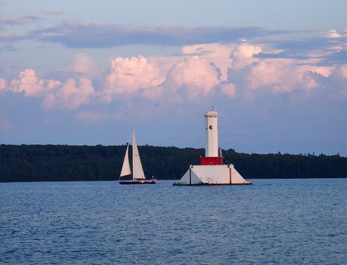 Dusk transforms the white passage light into a canvas for golden hour, while boats squeeze in one last journey before darkness falls.