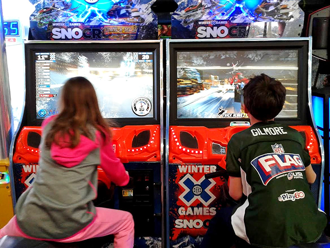 Young racers lean into the curves at the SnoCross arcade game, where winter racing thrills require no actual snow or safety gear.