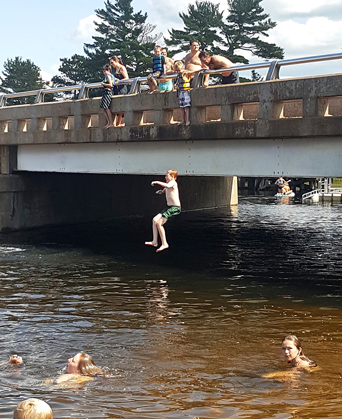 Local tradition comes alive as youngsters take the plunge from the bridge, creating summer memories that last a lifetime.