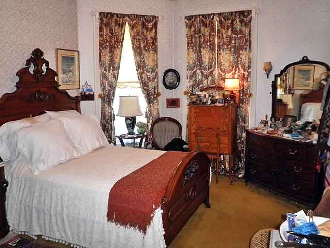 A bedroom that tells stories of bygone comfort &ndash; heavy furniture, layered textiles, and personal touches from another century.