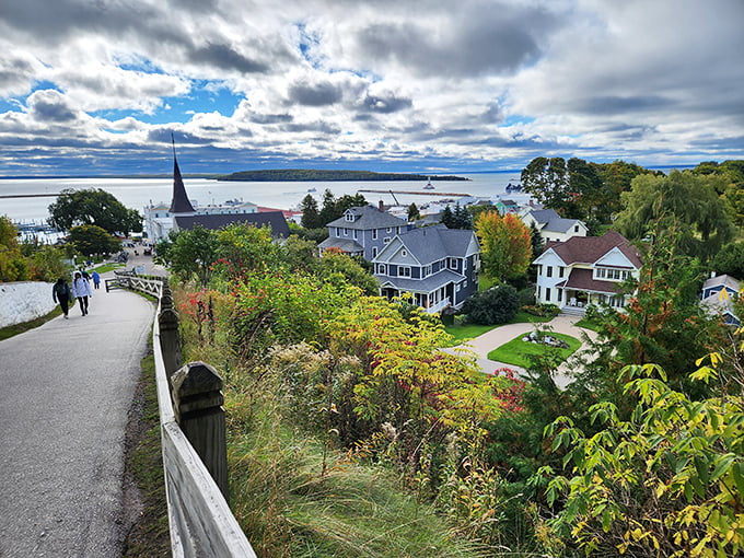 The island's elevated pathways reveal a patchwork of Victorian homes nestled among autumn foliage, with Lake Huron's endless blue horizon completing the scene.