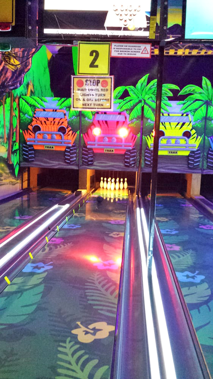 Jungle-themed bowling lanes offer a tropical twist on the classic game, with colorful jeeps replacing traditional bowling imagery.