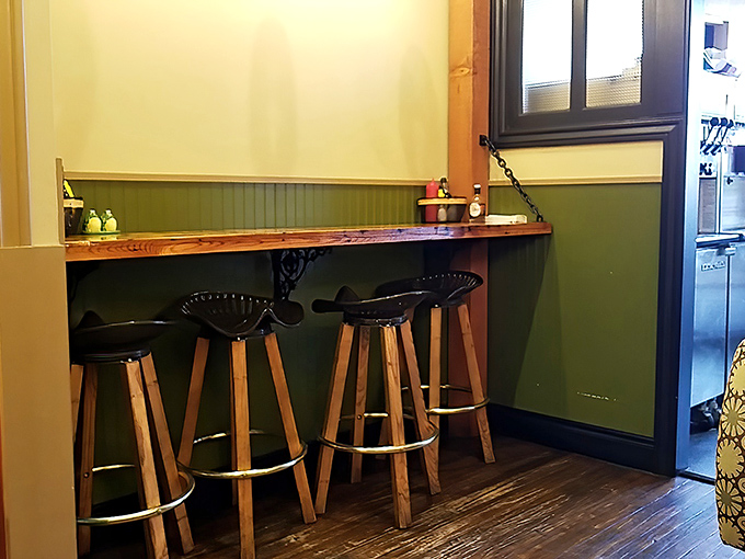 A cozy nook with wooden stools provides the perfect perch for solo diners to contemplate life's big questions, like "How are these fries so good?"