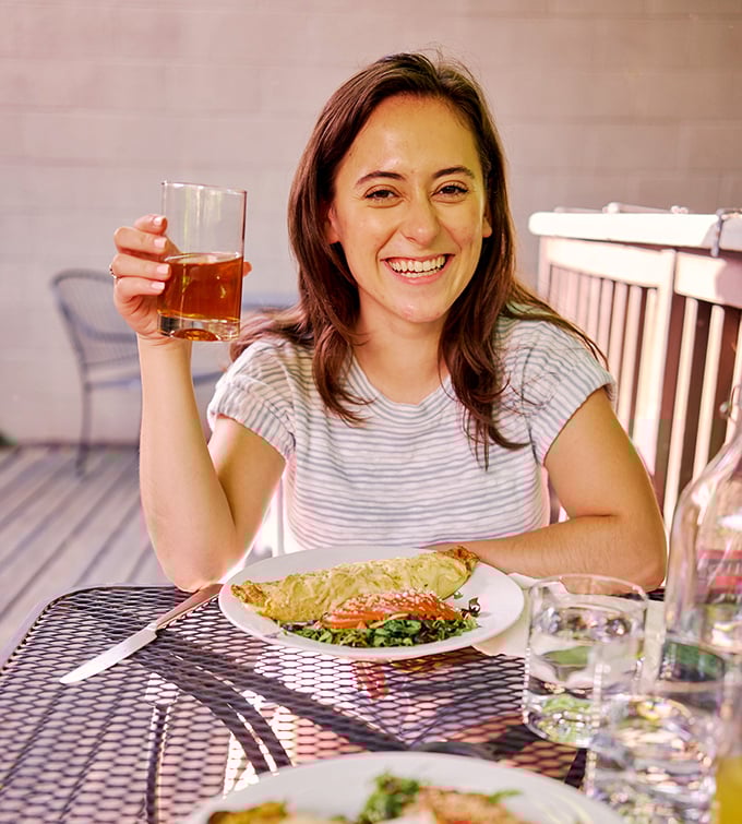 A diner enjoys the perfect bite of quiche alongside a refreshing beverage &ndash; the simple joy of French cuisine captured in a moment.