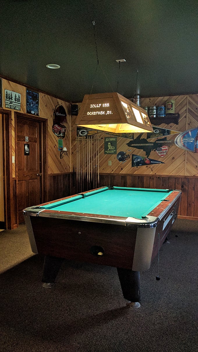 The pool table stands ready for friendly competition, illuminated by a custom Jolly Inn light fixture that casts a warm glow.